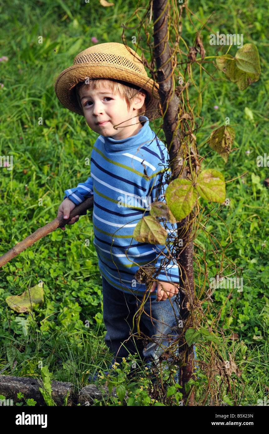 Little boy with straw hat playing in vegetable garden Stock Photo - Alamy