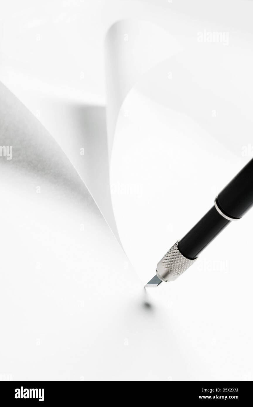 white sheet of paper being cut by a blade knife Stock Photo - Alamy