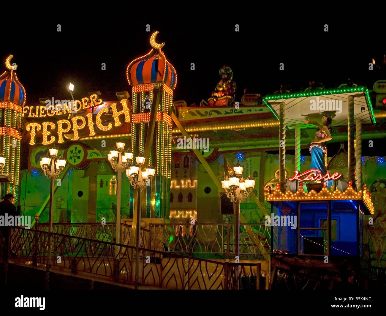 fair with lightened racing amusement rides in different colours in the ...