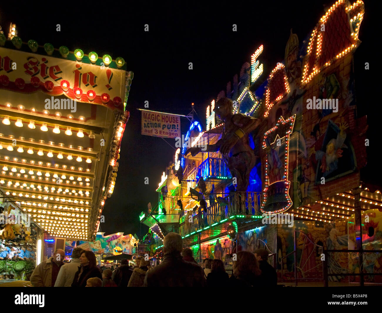 fair with lightened racing amusement rides in different colours in the ...