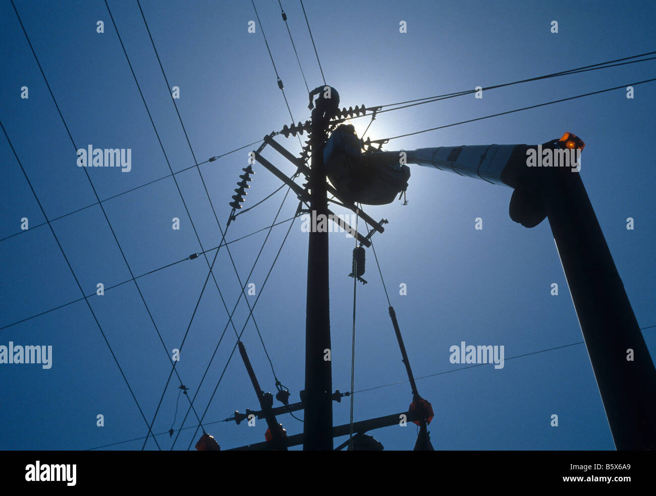 Electrical workers in cherry picker crane work on high tension power ...