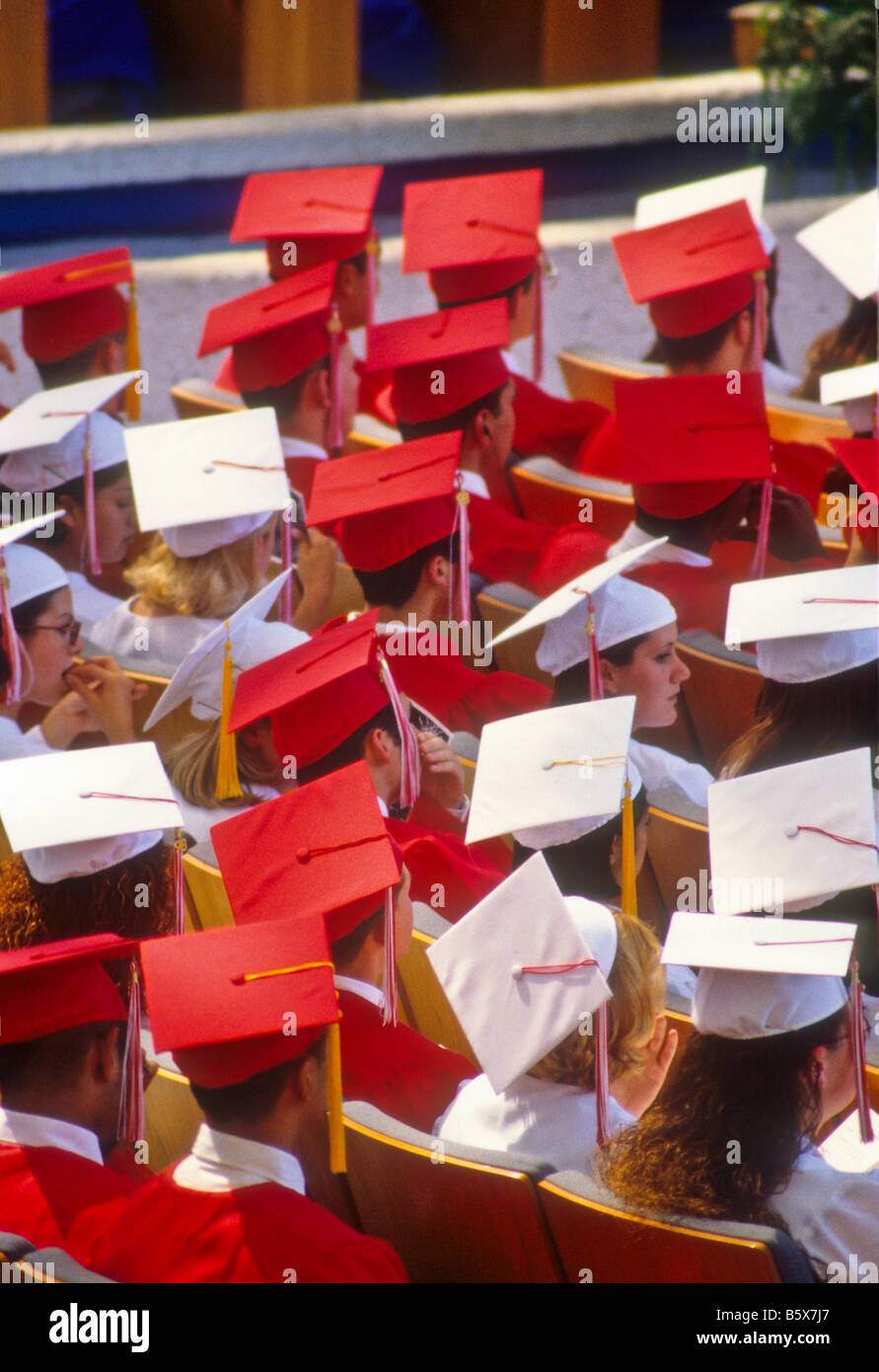 Red and white caps and gowns of graduates in ceremony at USA school ...