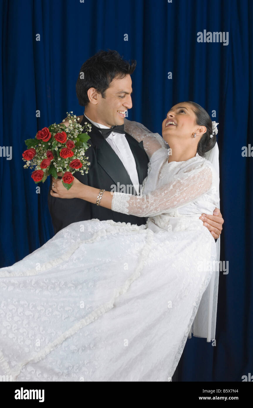 Bridegroom carrying his bride and smiling Stock Photo - Alamy