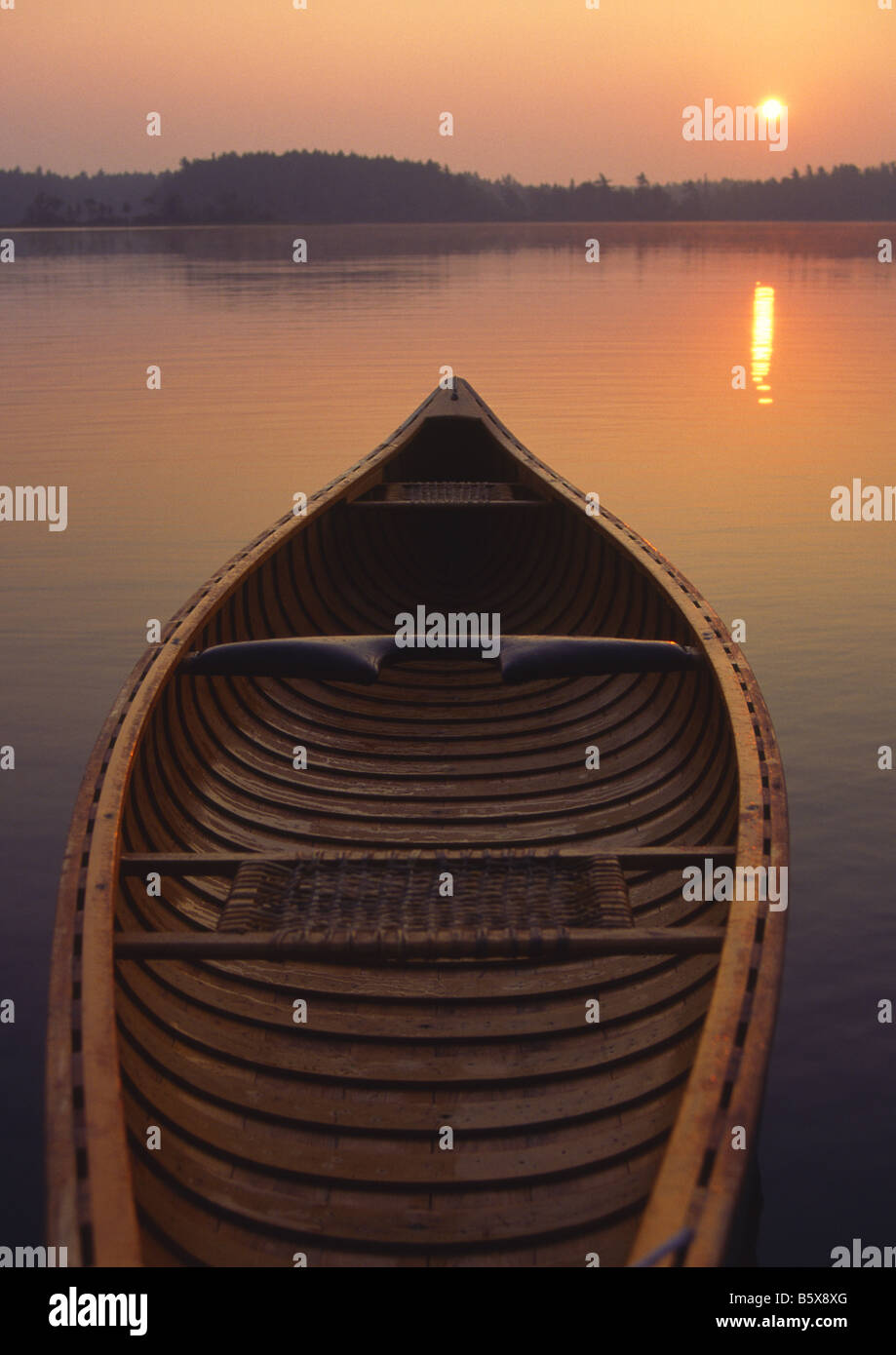 an open Canadian cedar canoe in the water on a lake at sunrise Stock ...