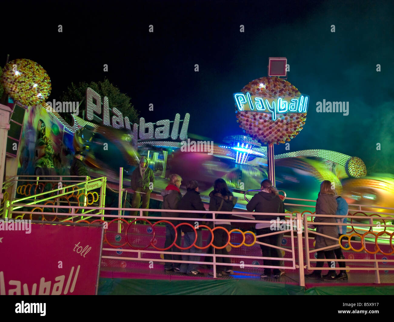 fair with lightened racing amusement rides in different colours in the ...