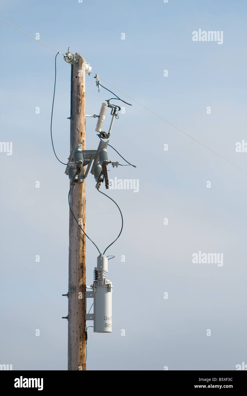 A close up of an electrical transformer on a power line with blue sky ...