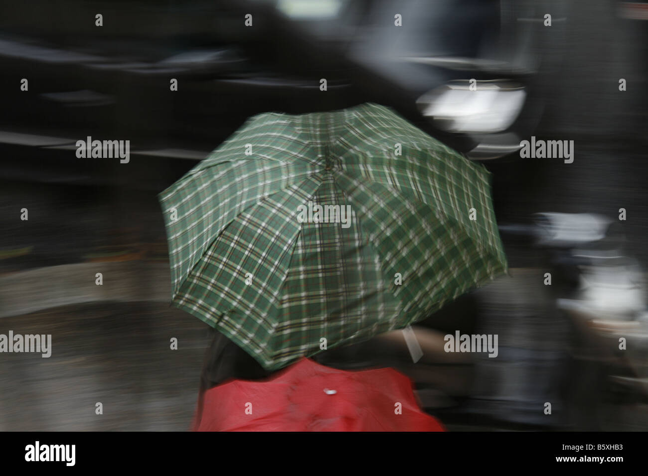 two people with colourful umbrellas in rain in town Stock Photo - Alamy