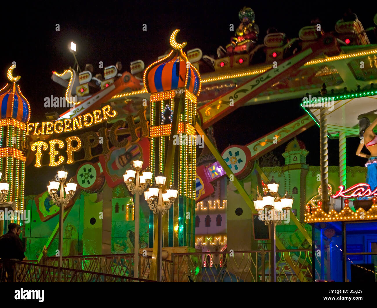 fair with lightened racing amusement rides in different colours in the ...