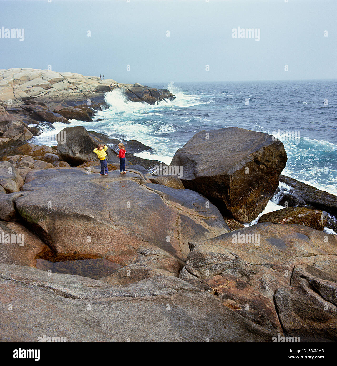 Two children playing on rocks at East Coast of Canada, Atlantic Ocean ...