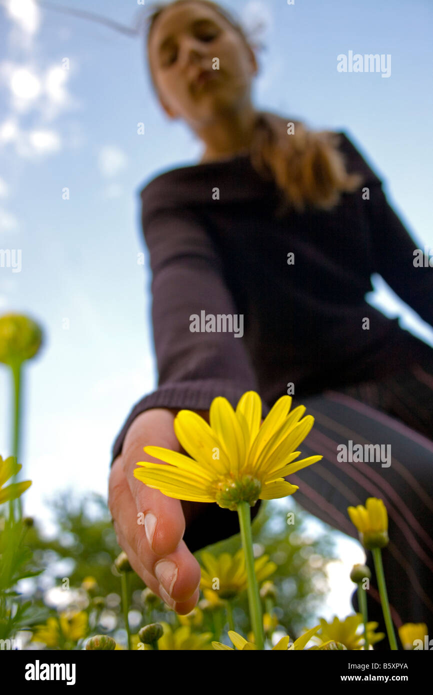 Teenage girl reaching to pick a flower Stock Photo - Alamy