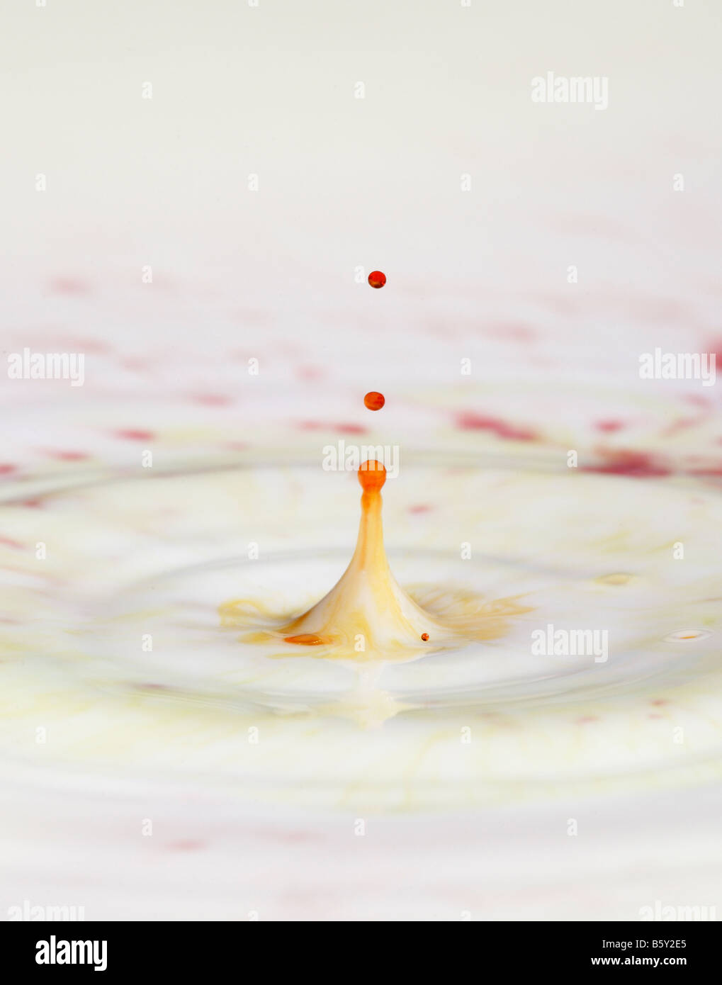 Milk drop splashing down with food dye Stock Photo - Alamy