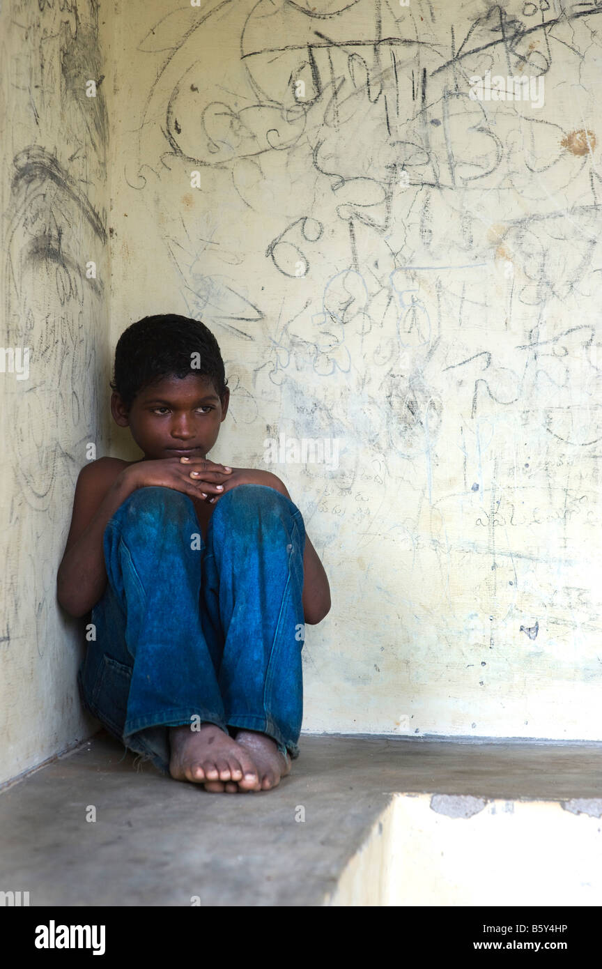 Sad Indian boy sitting against a wall covered in graffiti Stock Photo ...