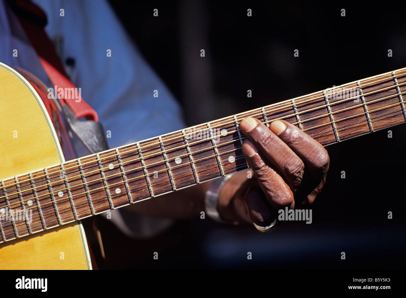 Black musician playing guitar on the street along the AVE University ...