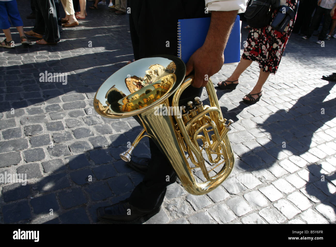 man carrying brass instrument in sun in street in town Stock Photo - Alamy