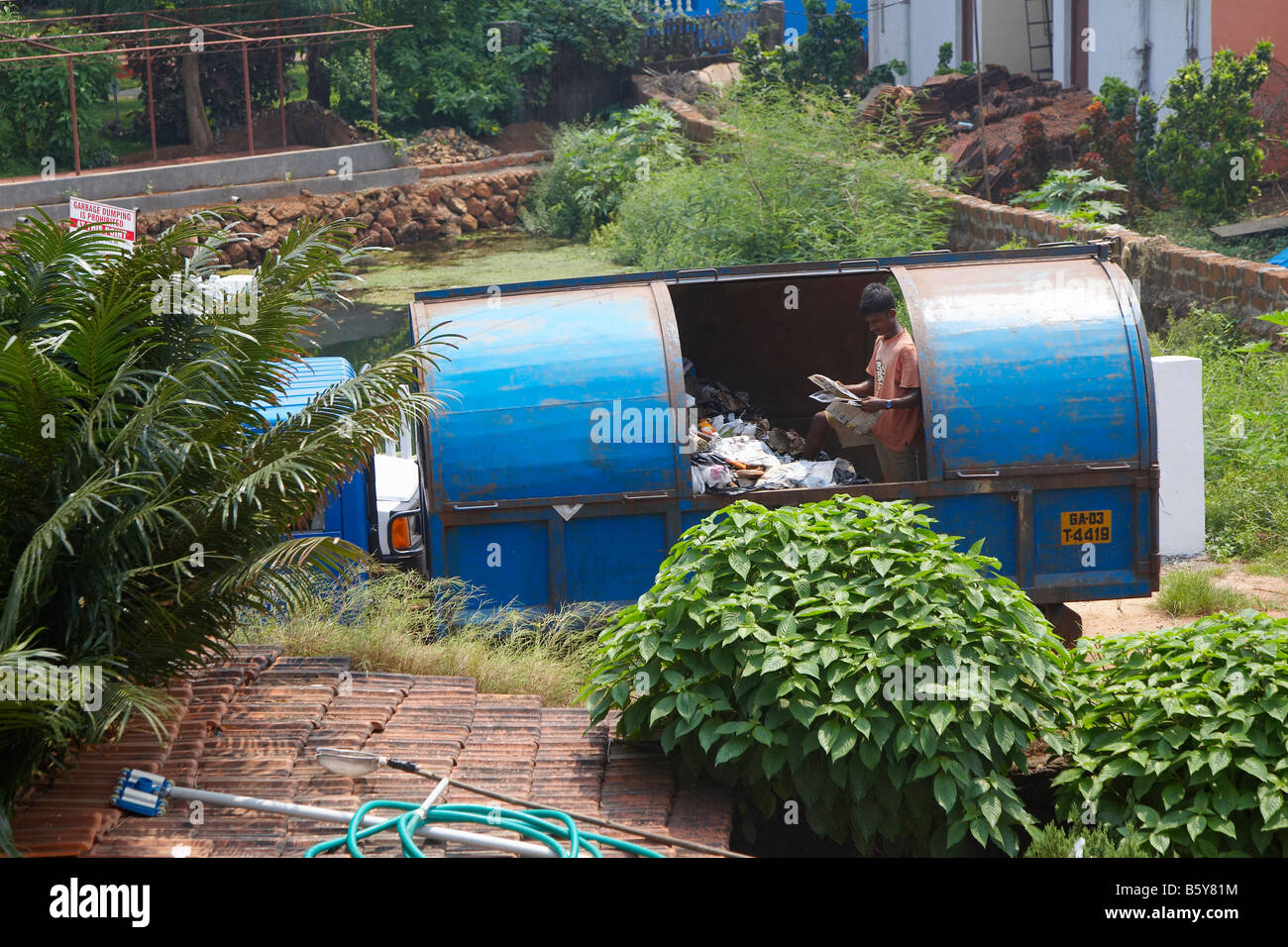 Binman reading an old newspaper inside garbage truck in Goa, India ...