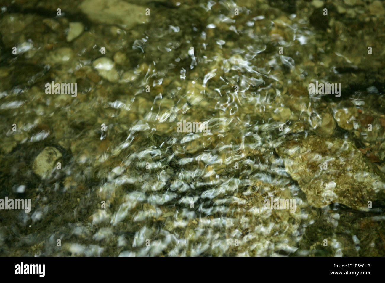 Water flowing over pebbles in a shallow stream wit Stock Photo - Alamy