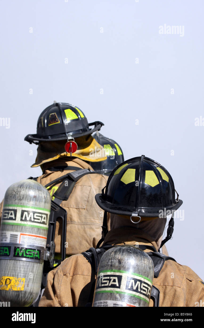 Three firefighters surrounded by smoke from a structure fire Stock ...