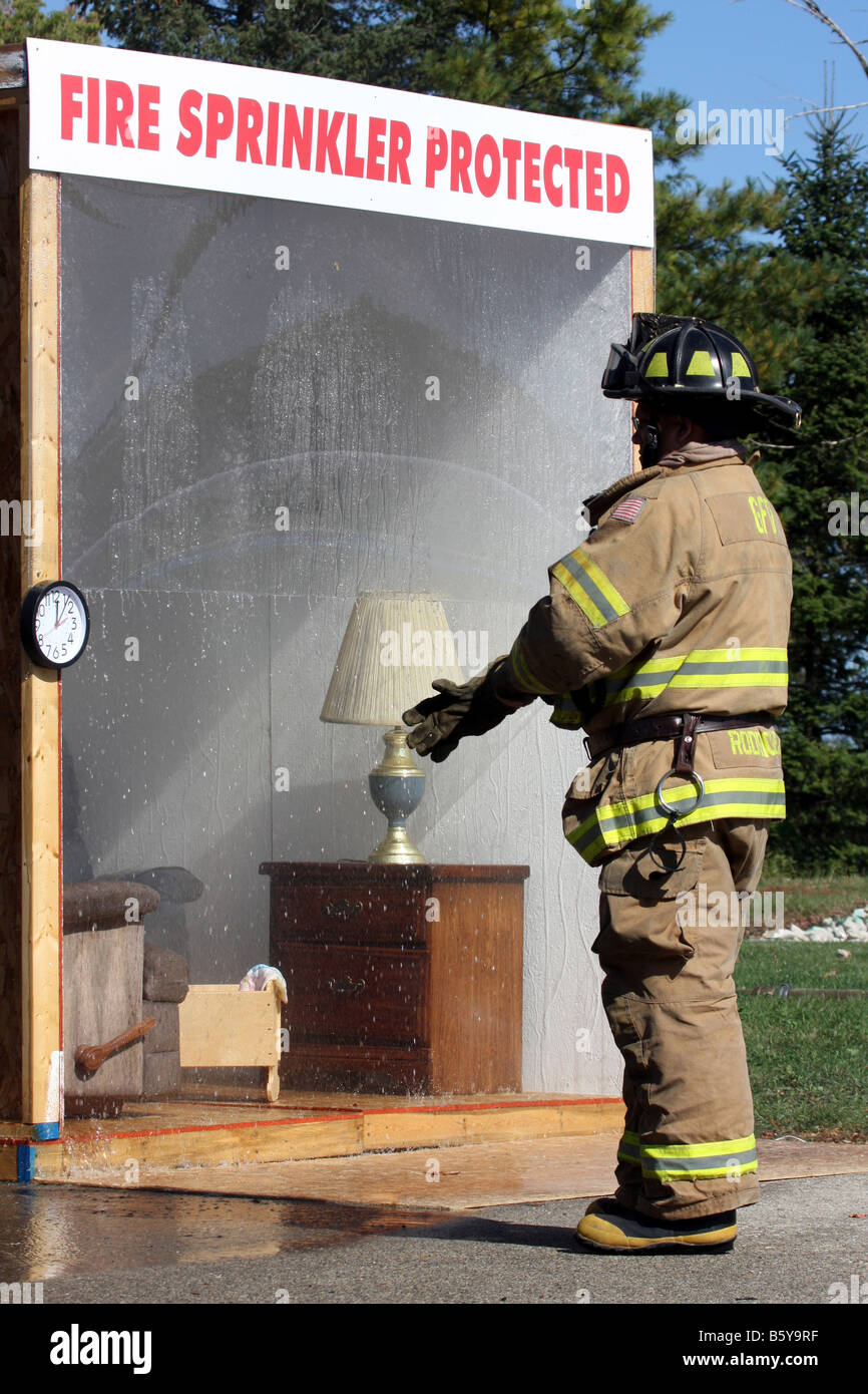 A firefighter in front of a display for a fire sprinkler demonstration ...