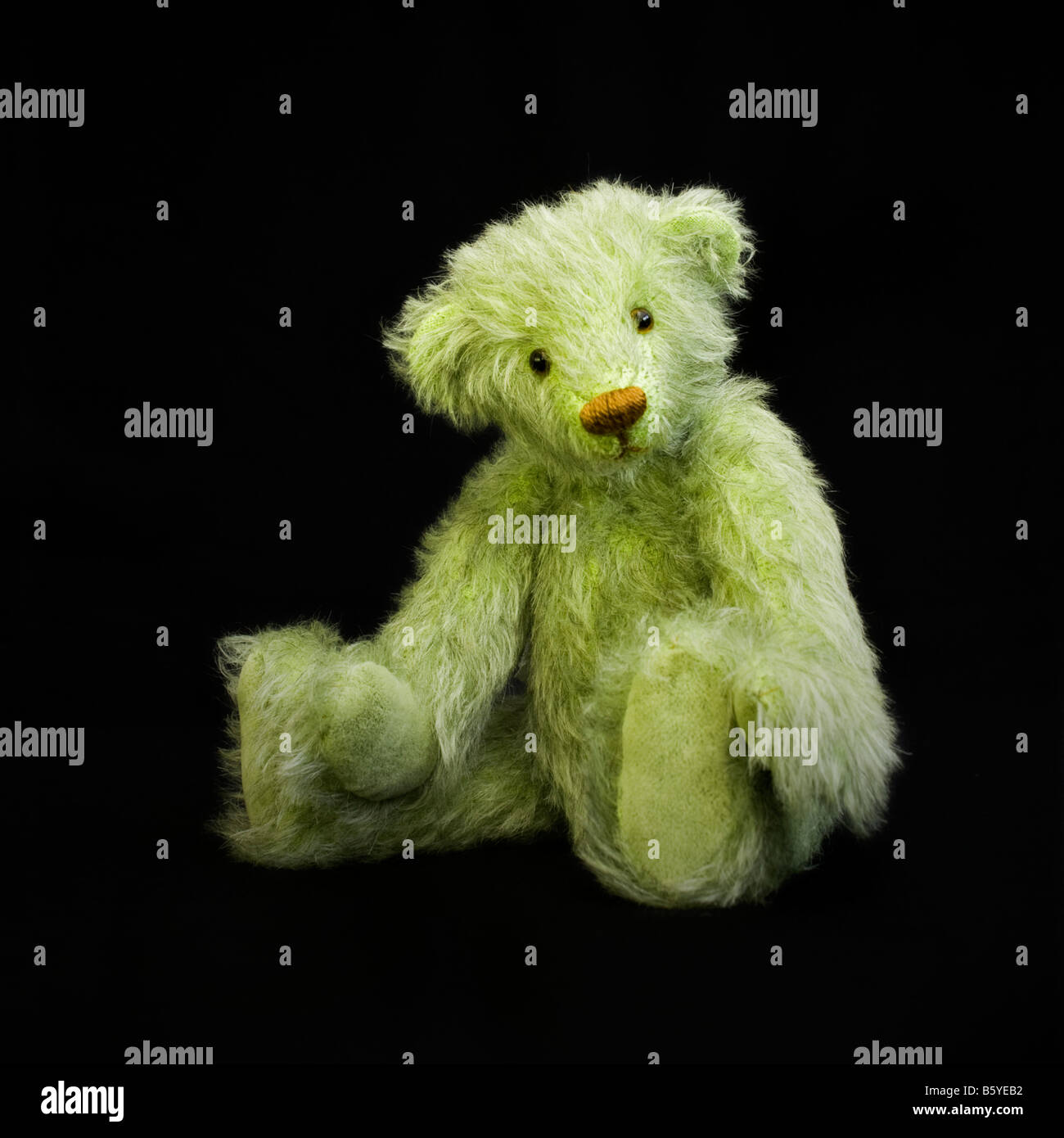 Hand made pale green teddy bear with orange sewn nose sitting on a ...