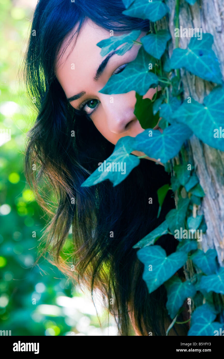 Young beautiful woman observing behind leaves Stock Photo - Alamy