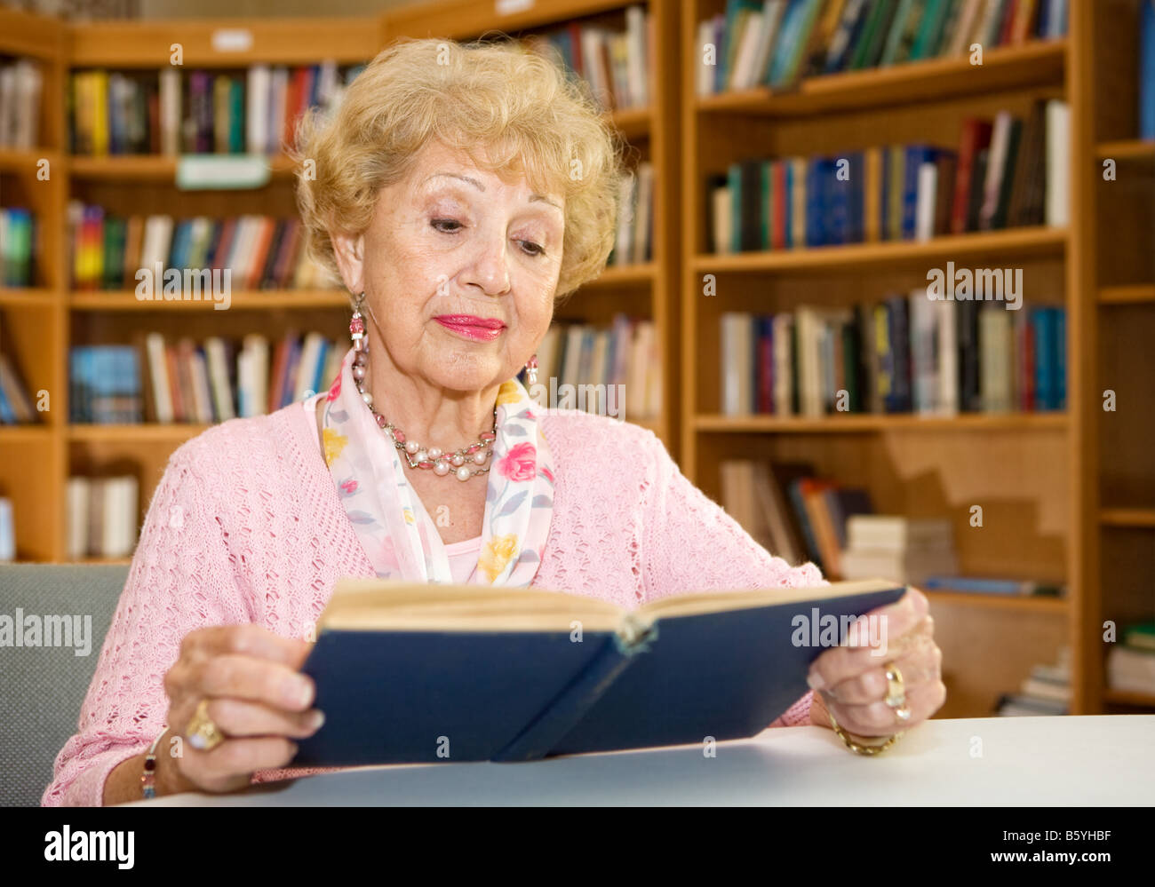 Beautiful senior student reading a book at the library Stock Photo - Alamy