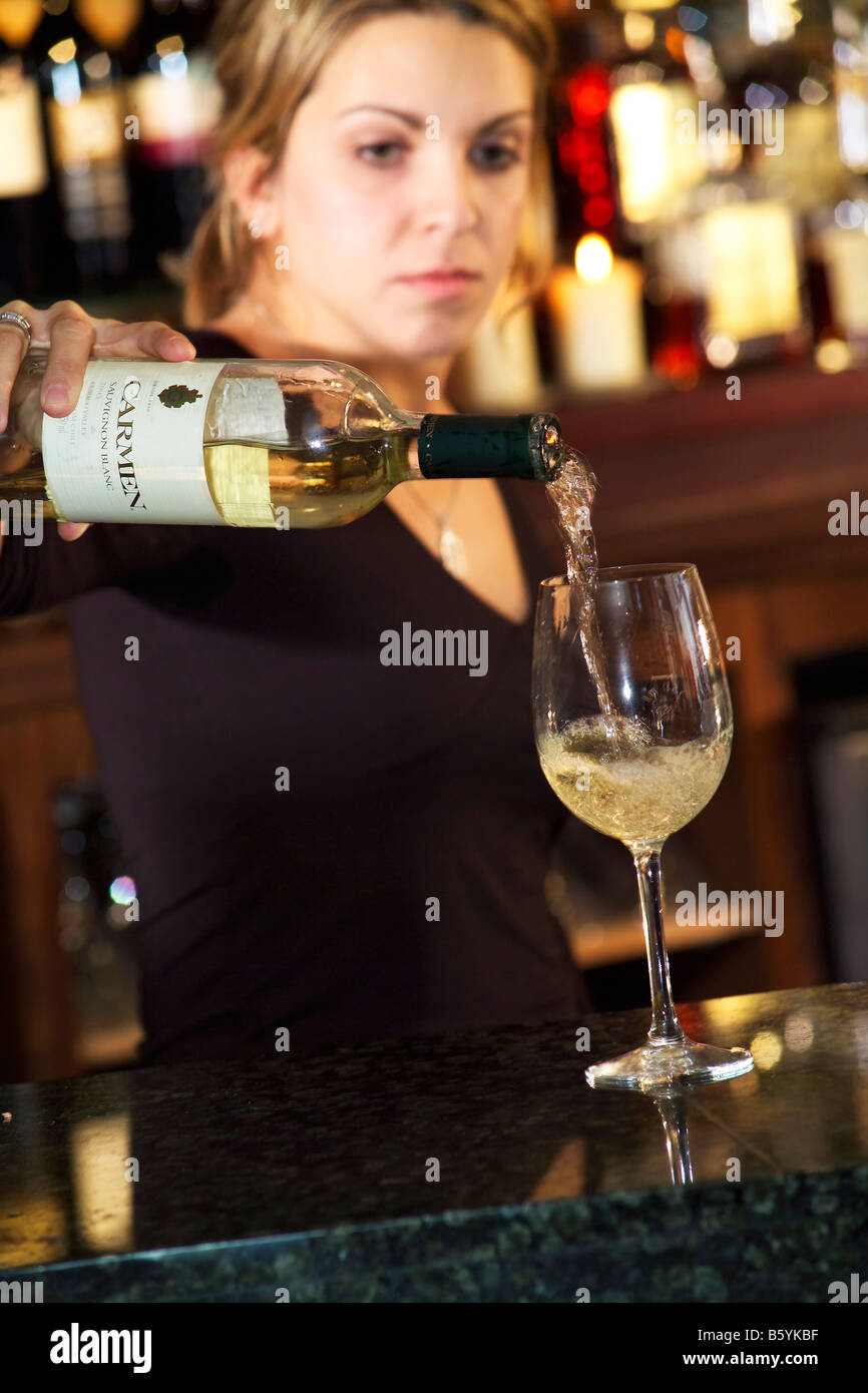 White wine being poured from bottle into glass Stock Photo - Alamy