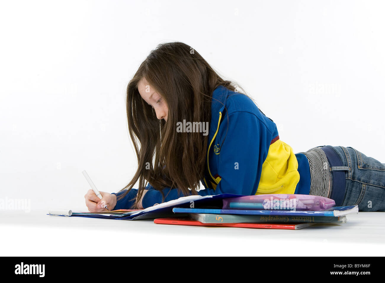 young girl doing her homework lying on the floor Stock Photo - Alamy