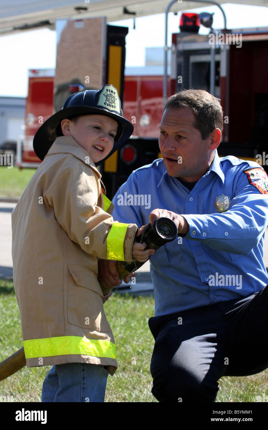 A firefighter and a junior firefighter child using a water hoseline at ...