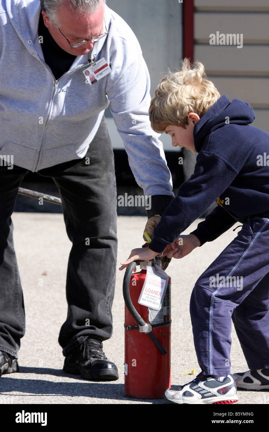 A child learning how to use an extinguisher at a Fire Safety Fair Stock ...