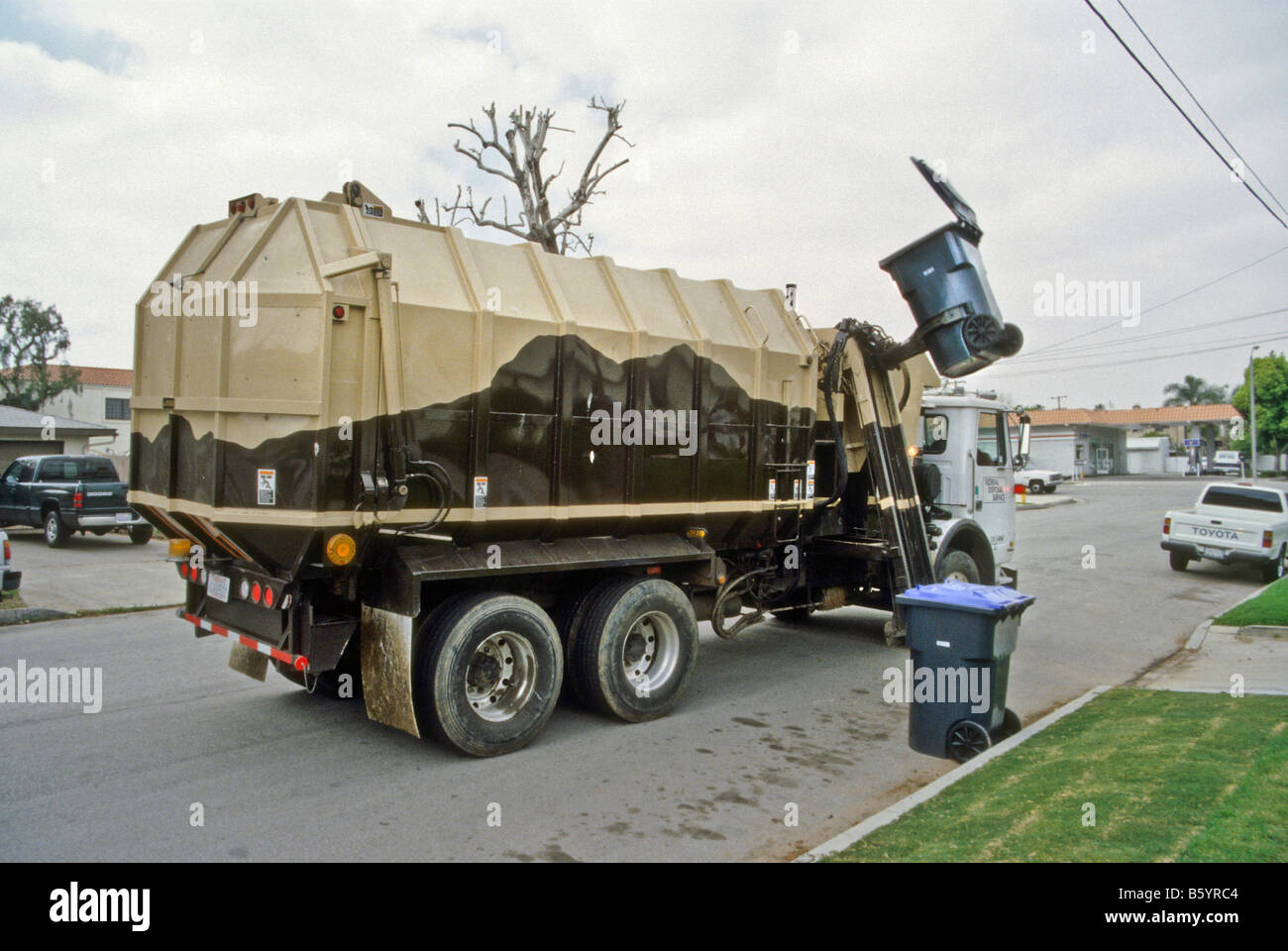 Trash truck uses mechanical arm to dump trash bins Stock Photo - Alamy