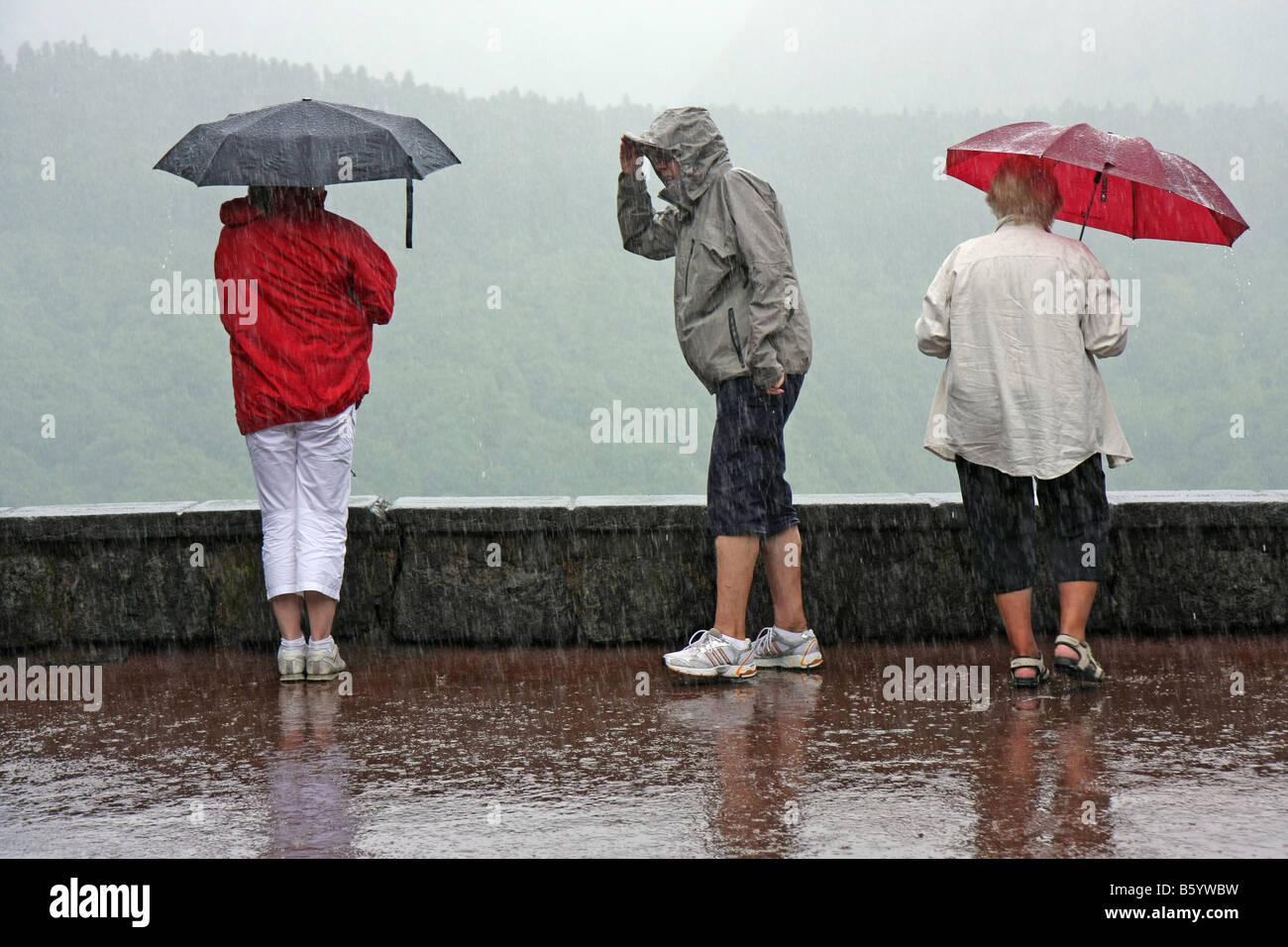 Tourists in heavy rain looking, down at the crater lake Lagoa de ...