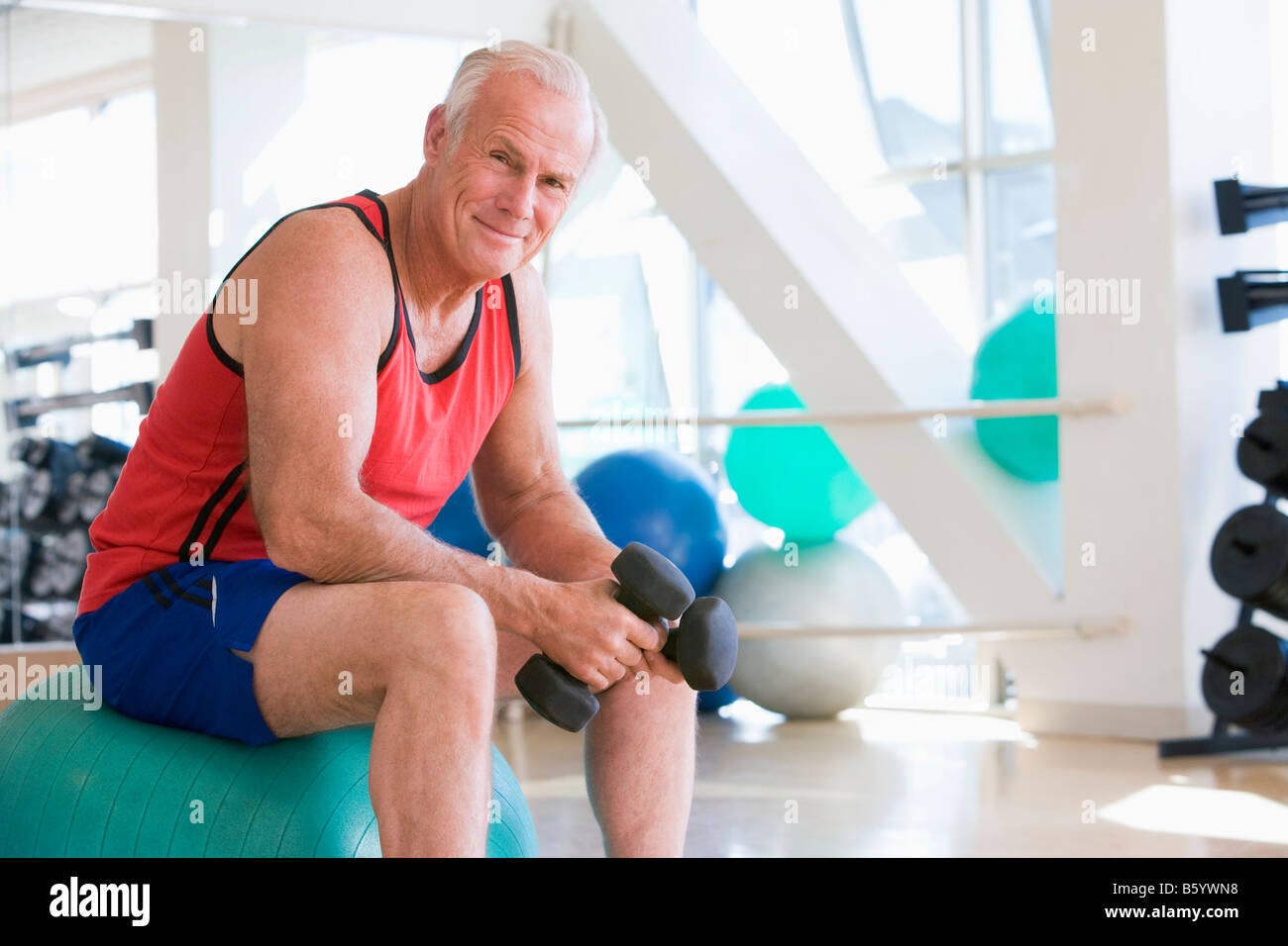 Man Using Hand Weights On Swiss Ball At Gym Stock Photo - Alamy
