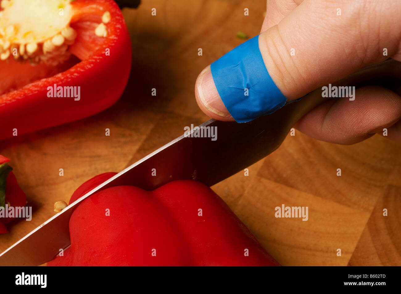 Man cutting red pepper with blue high visibility sticking plaster on ...