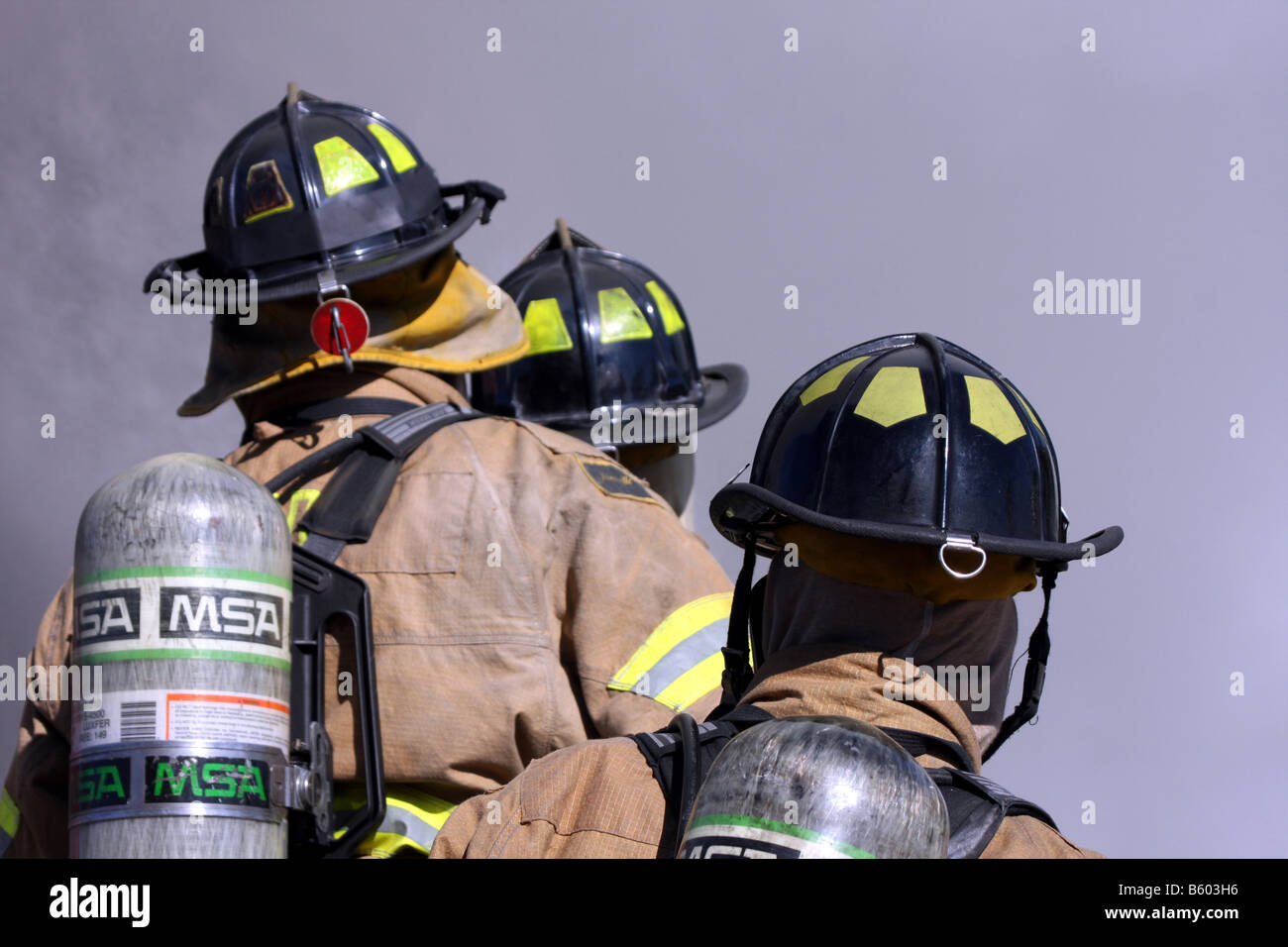 Three firefighters fighting a fire scene with smoke surrounding them ...