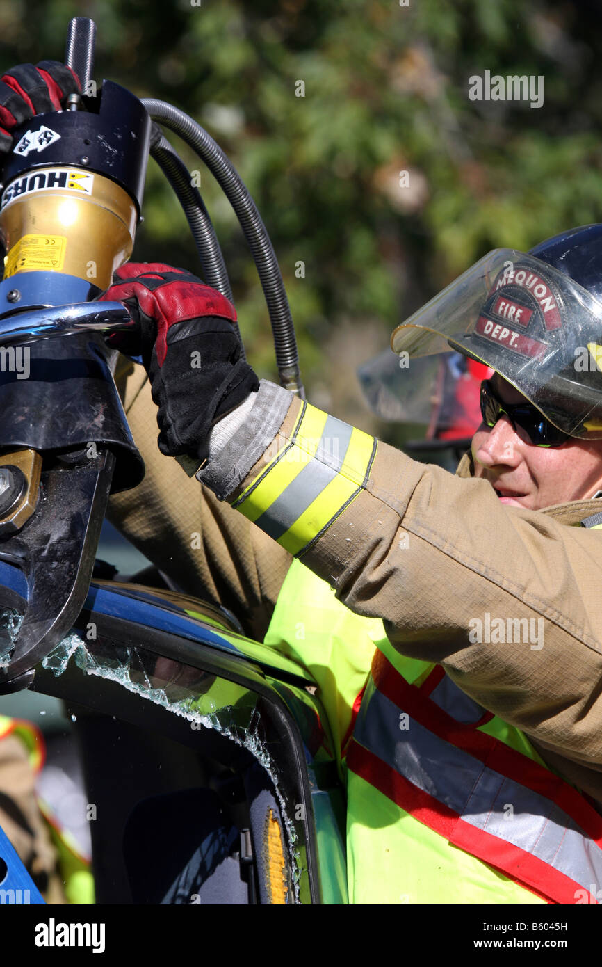 A firefighter is using the jaws of life extrication tool to cut through ...