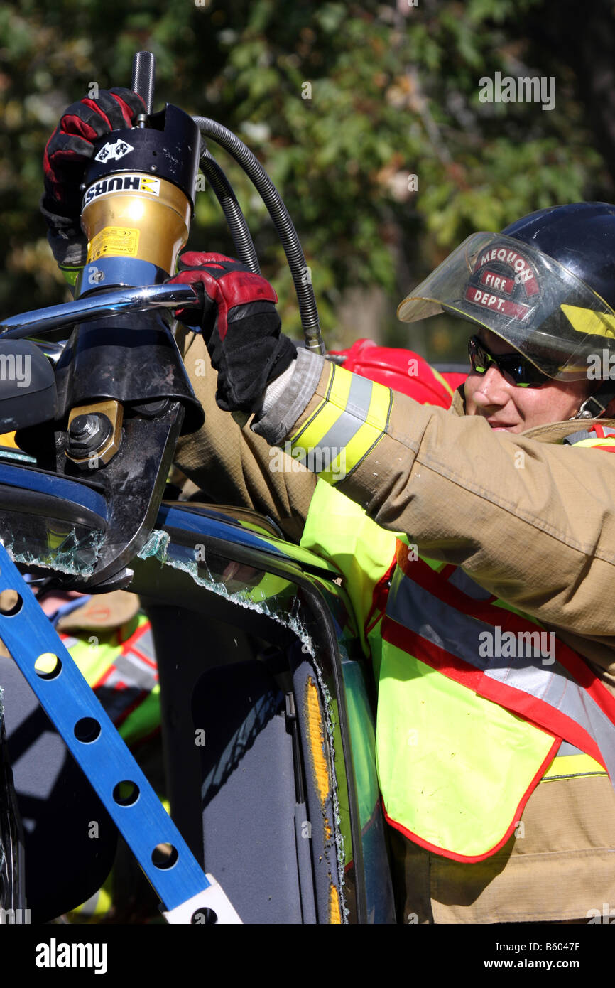 A firefighter is using the jaws of life extrication tool to cut through ...