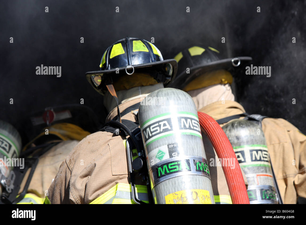 Three firefighters fighting a fire Stock Photo - Alamy