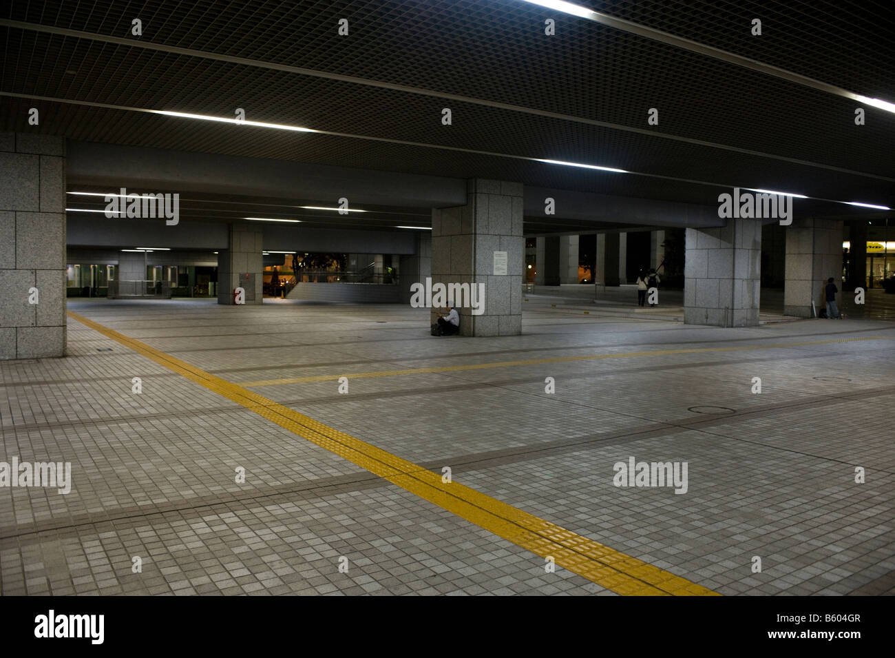 Japanese businessman sitting against a pillar in an underpass in ...
