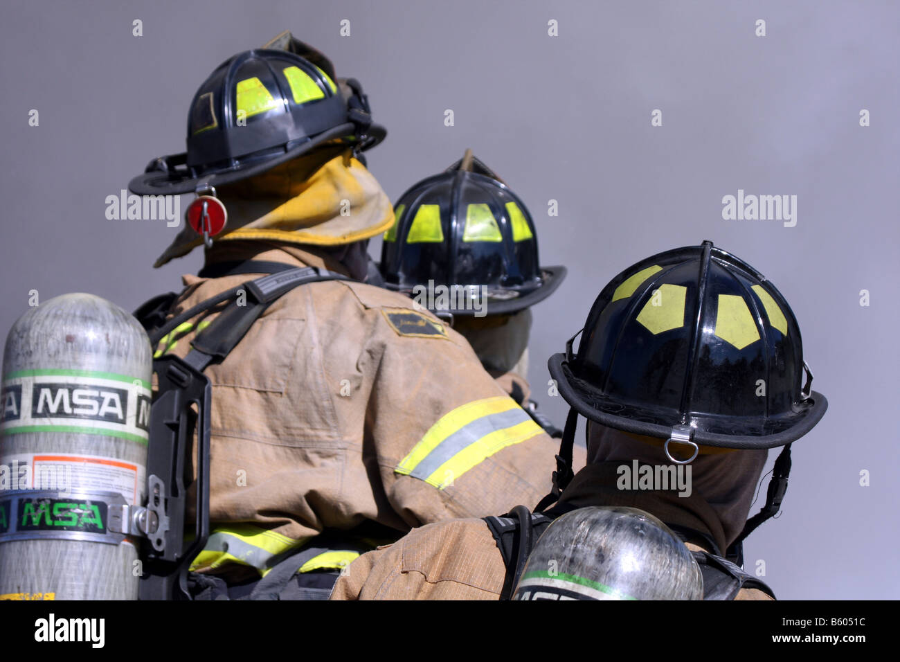 Three firefighters fighting a fire scene with smoke surrounding them ...