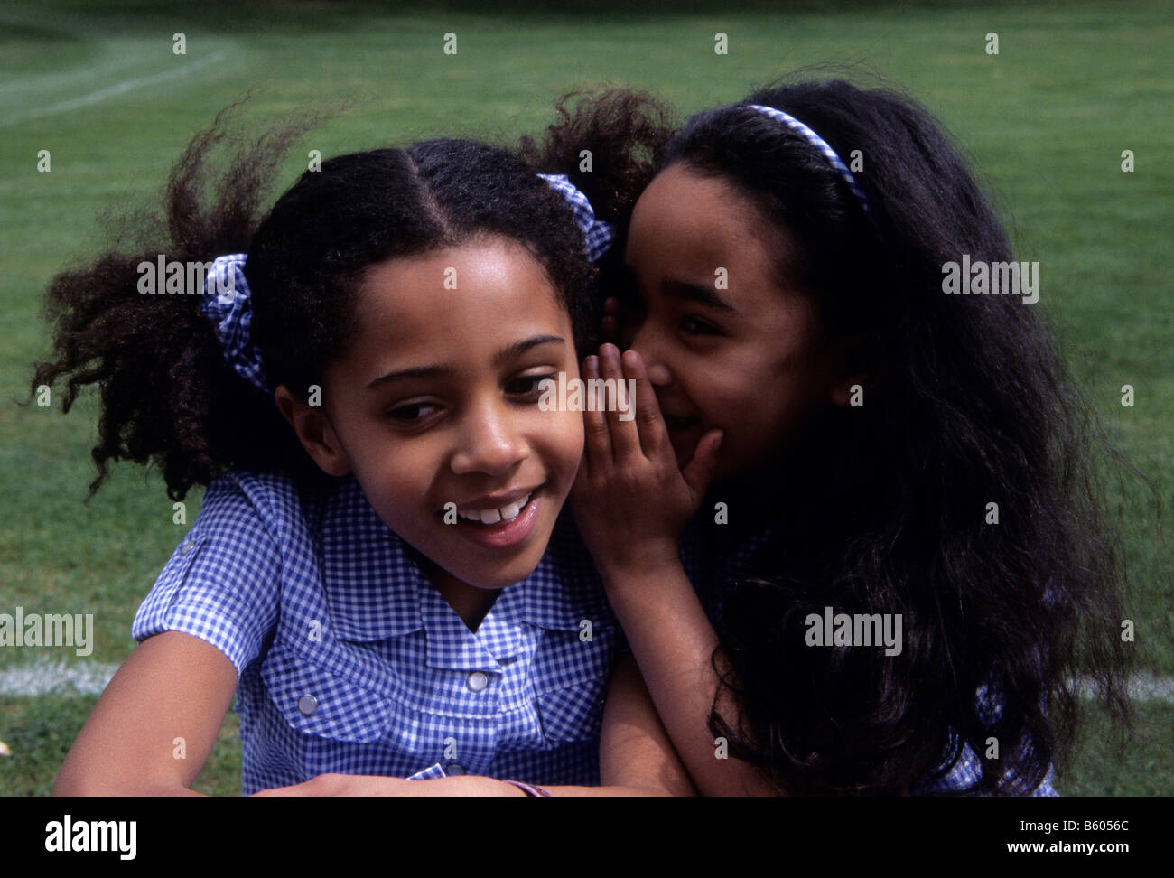 Two schoolgirls sharing secrets with each other Stock Photo - Alamy