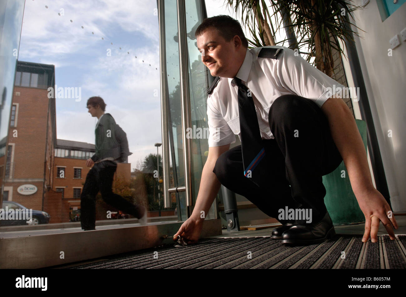 A SECURITY GUARD ON PATROL UNLOCKS THE DOOR OF A BUSINESS PREMISES UK ...