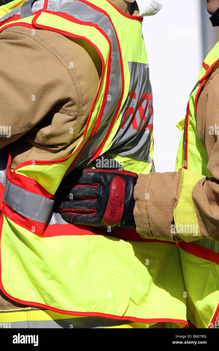 A firefighter giving support with a hand to the back of another ...