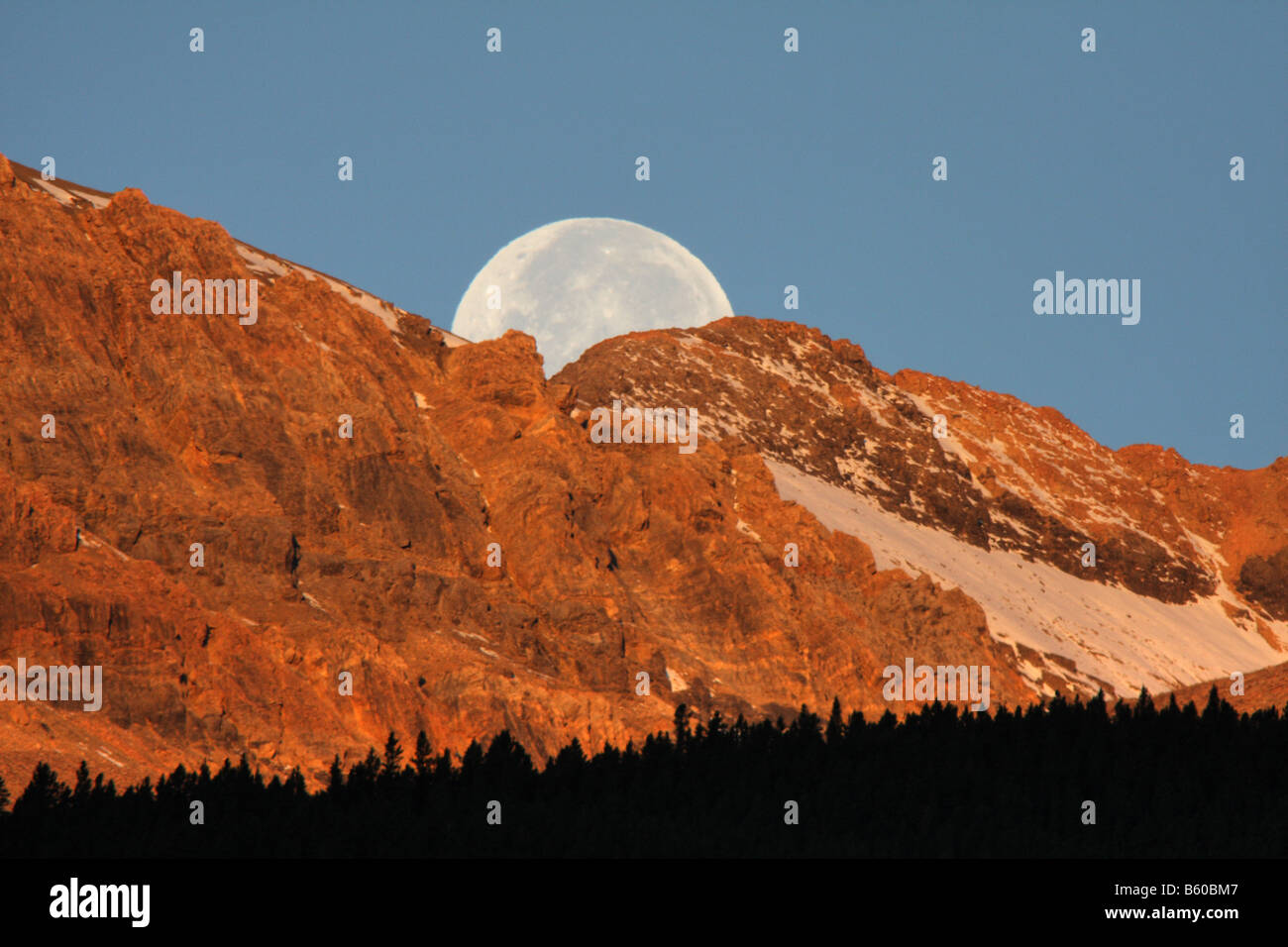 Full moon behind mountain in scenic Alberta Stock Photo - Alamy