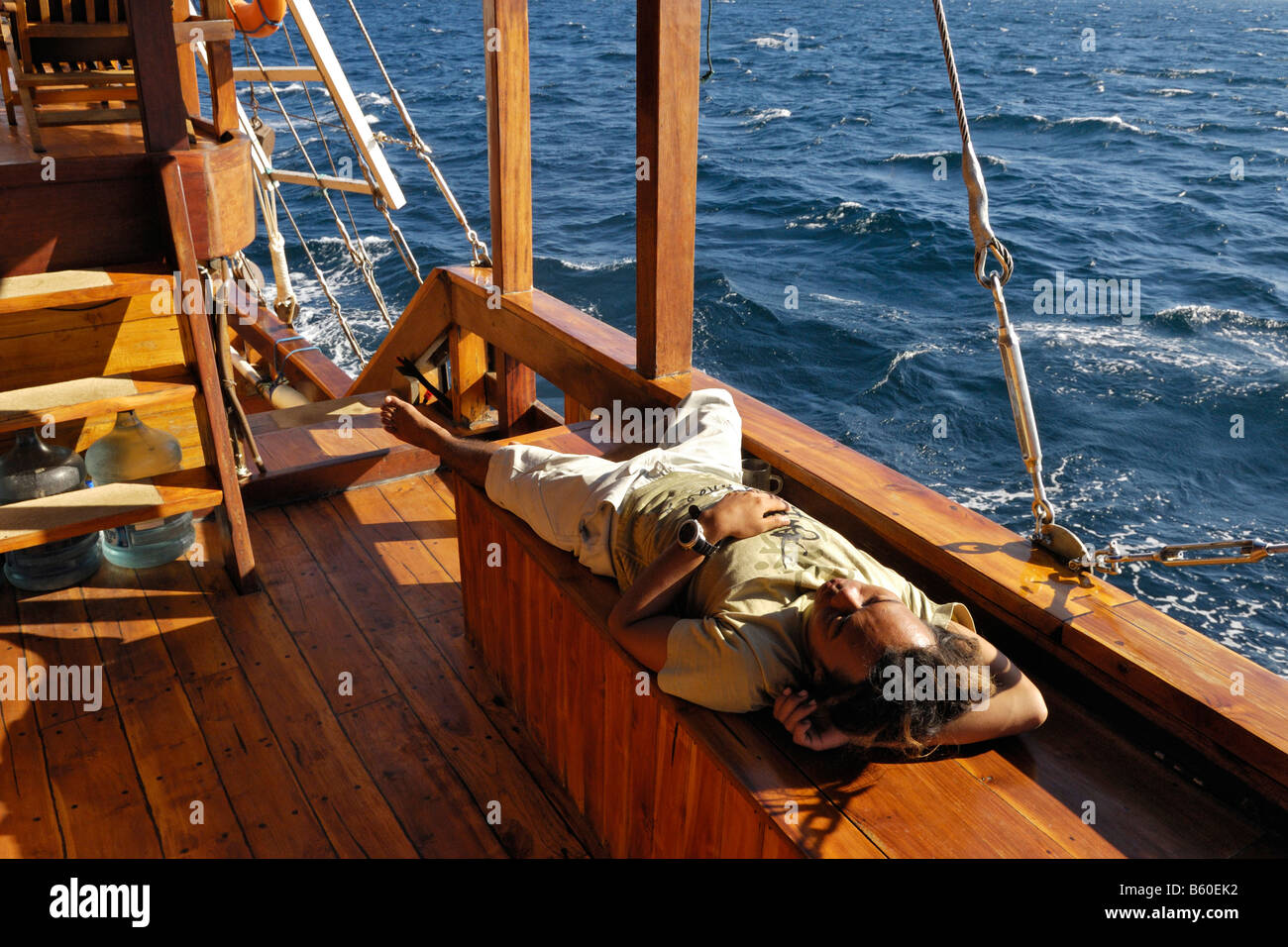 Divemaster relaxing on the deck of the MS-Felicia, Komodo National Park ...