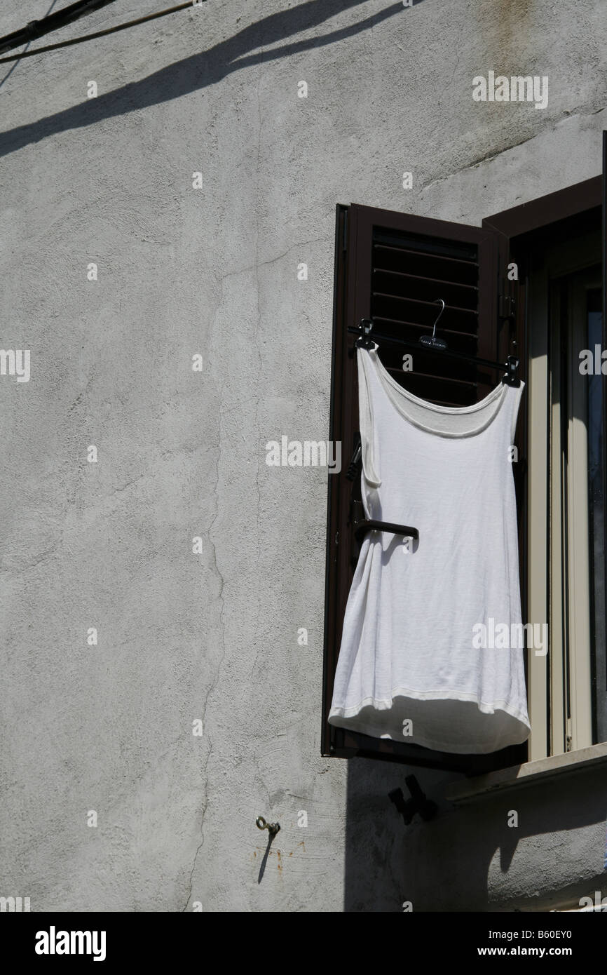 one white vest on washing line outdoors in apartment block in sun in ...