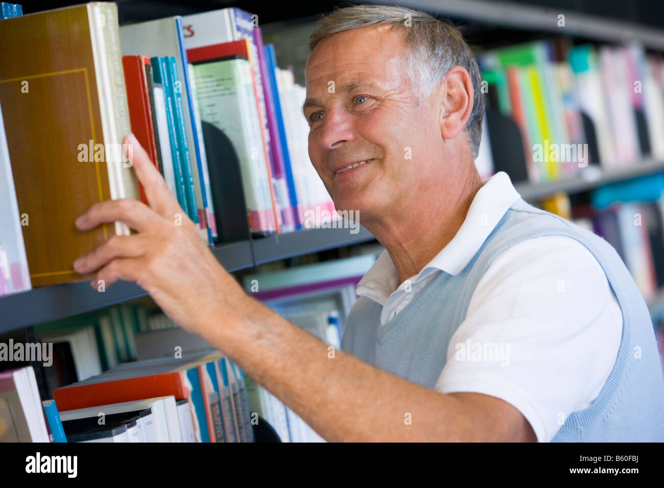 Man in library pulling book off a shelf (depth of field Stock Photo - Alamy