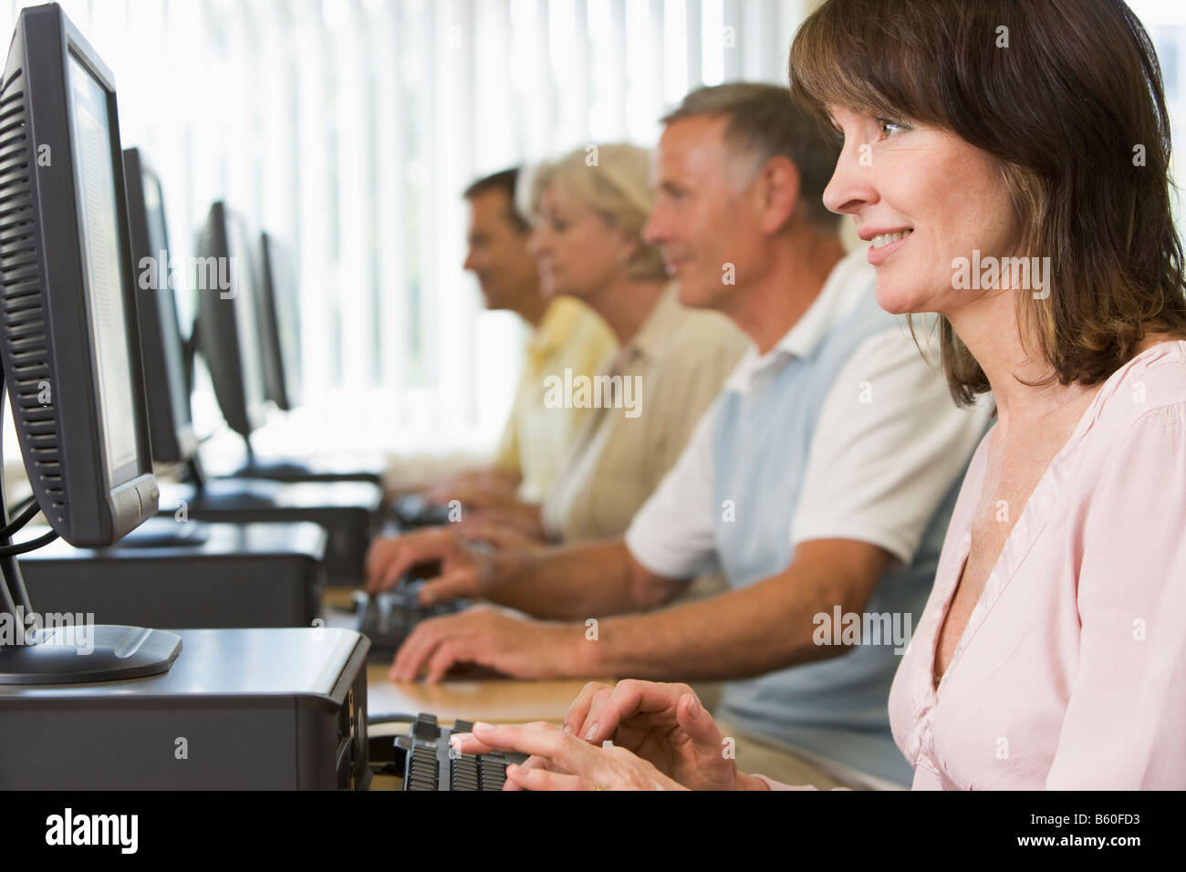 Four people sitting at computer terminals (depth of field/high key ...