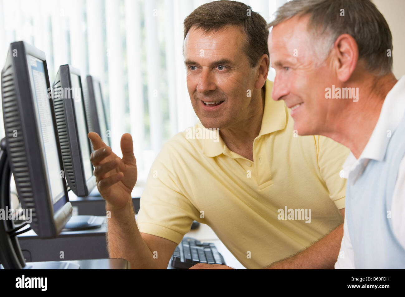 Two men at a computer terminal talking (depth of field/high key Stock ...