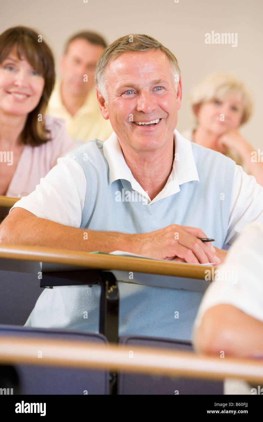 Man sitting in adult classroom laughing with students in background ...