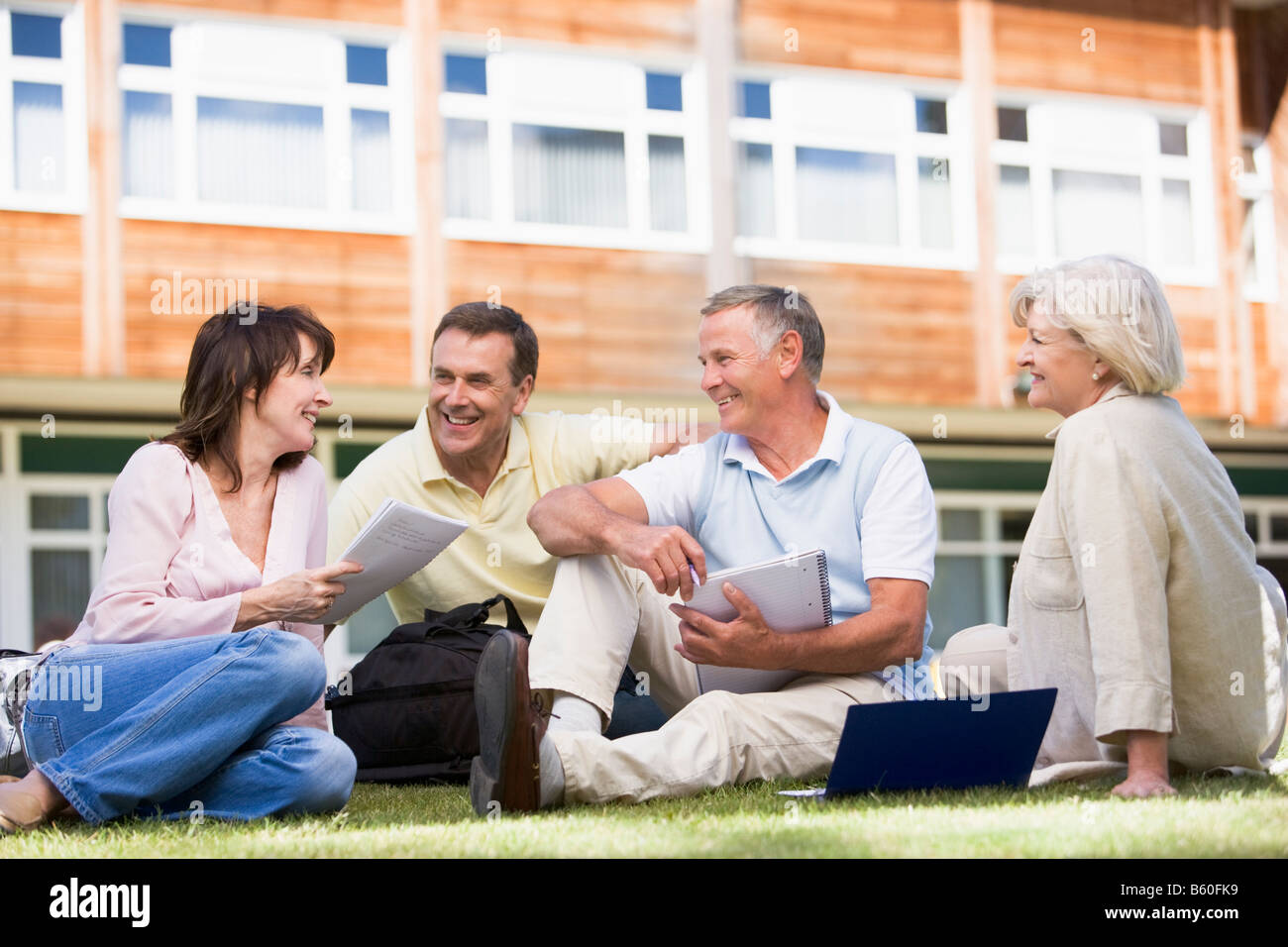 Adult students on lawn of school studying and talking Stock Photo - Alamy